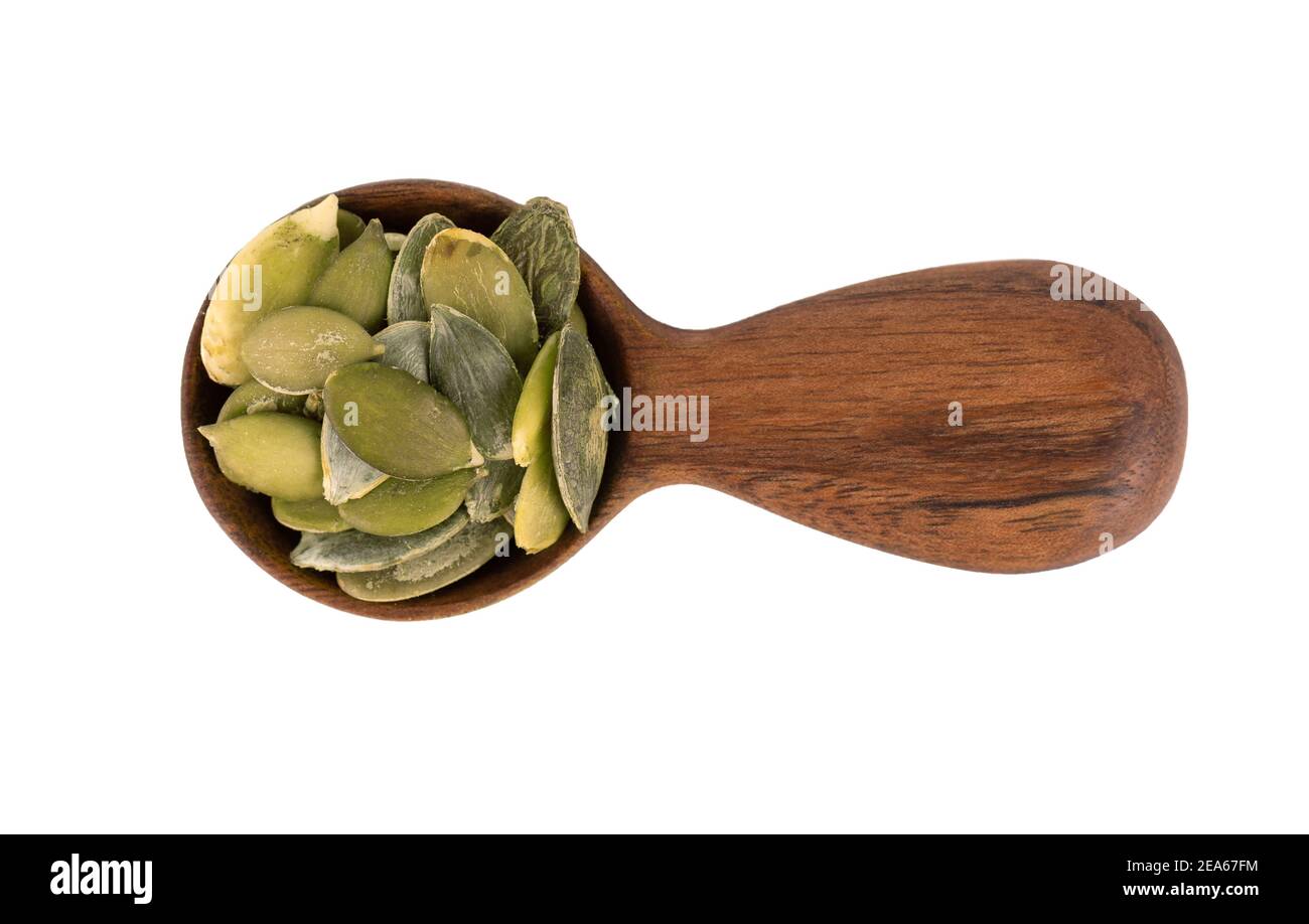 Pumpkin seeds in wooden spoon, isolated on white background. Green ...