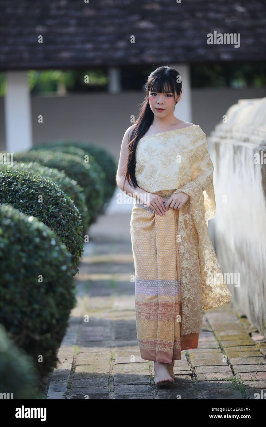 Portrait of Thai female with traditional Thai dress walking with temple ...