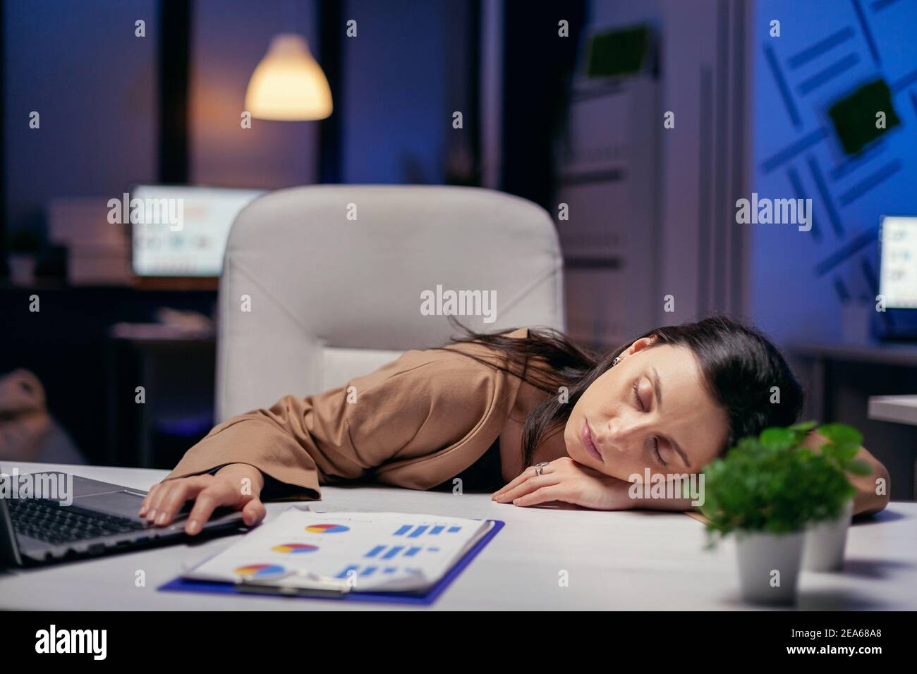 Tired businesswoman resting head on desk holding hand on laptop ...