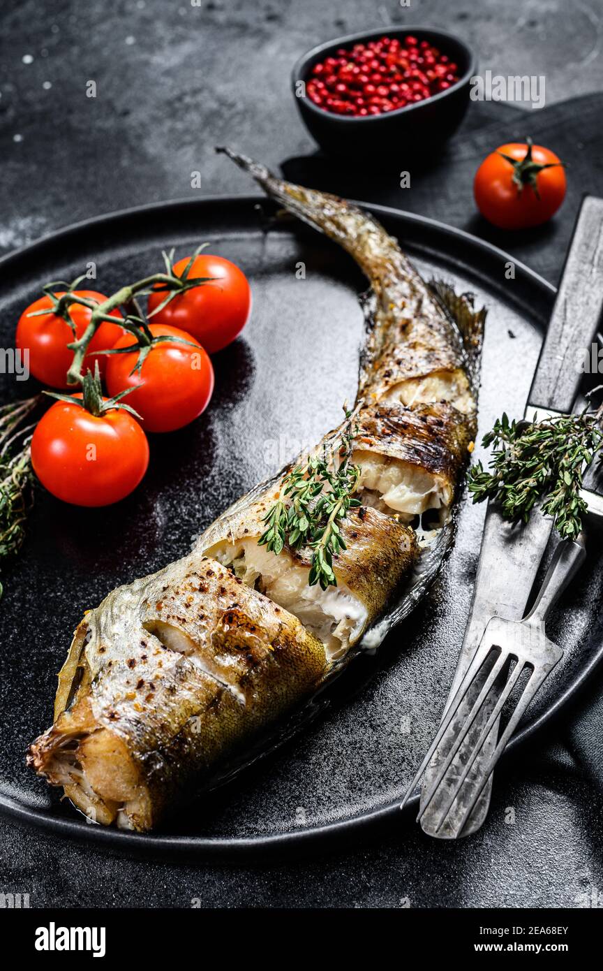 Baked pollock cooked in a savory marinade. Black background. Top view ...