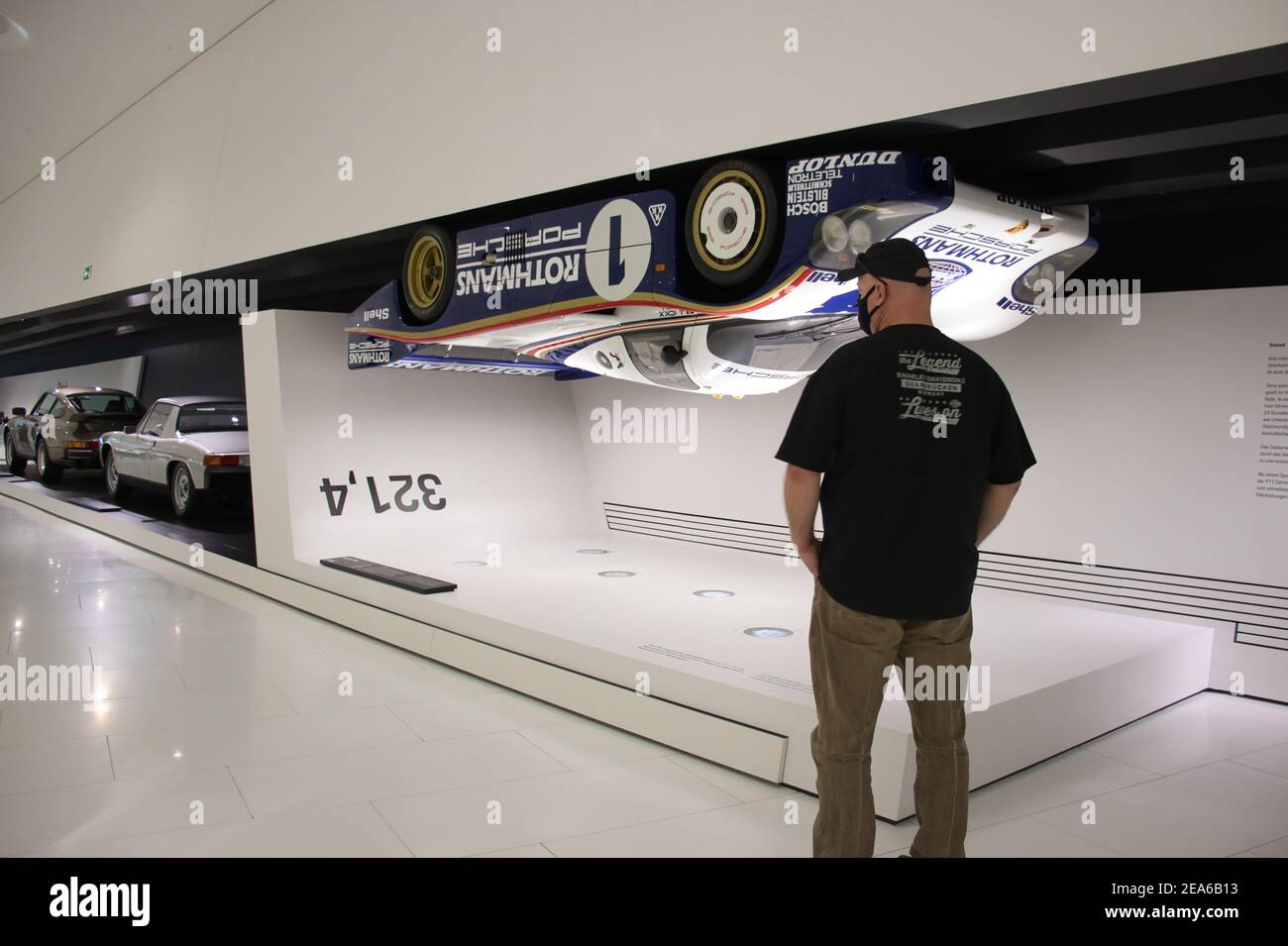 Man looking at an upside down car hanging in the Porsche museum in ...