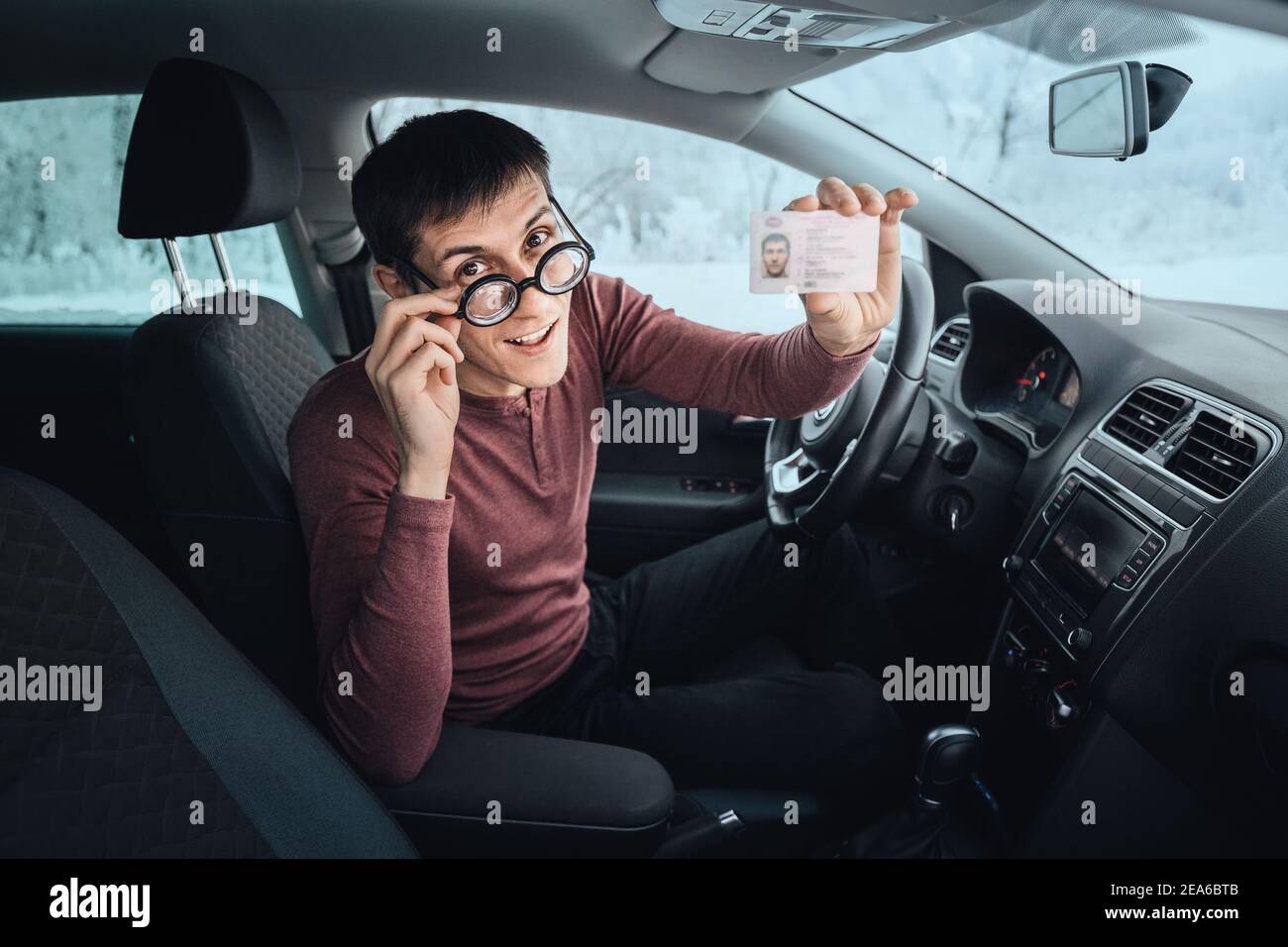 Funny nerd and geek in huge ridiculous glasses shows his driver's ...