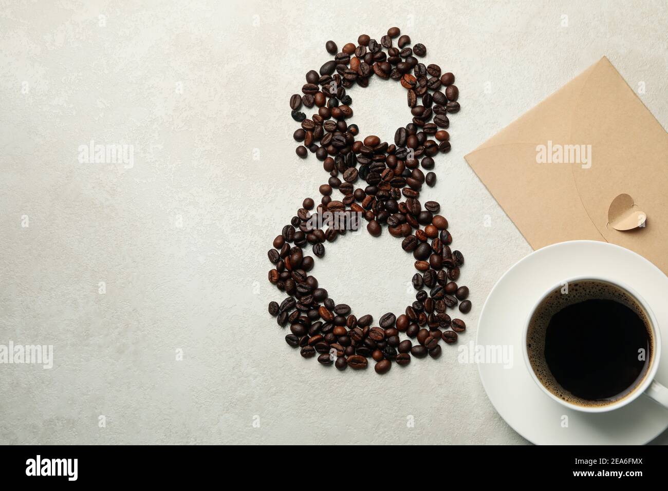 Eight made of coffee beans, cup of coffee and envelope on white ...