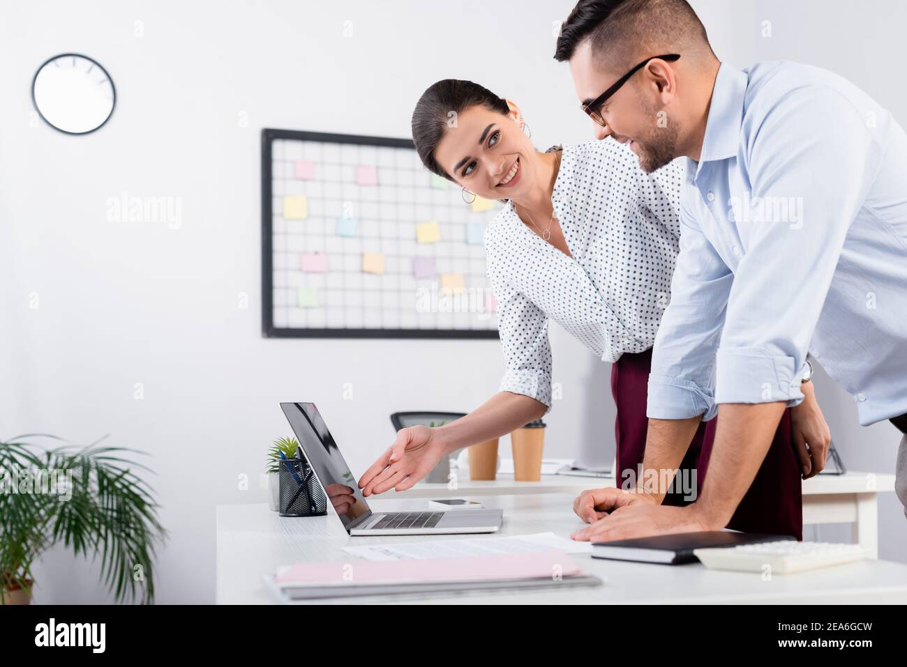 happy businesswoman pointing with hand at laptop with blank screen on ...