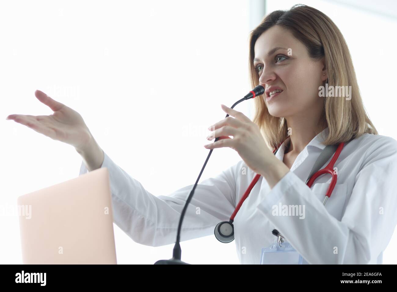 Woman doctor speaking into microphone at presentation Stock Photo - Alamy