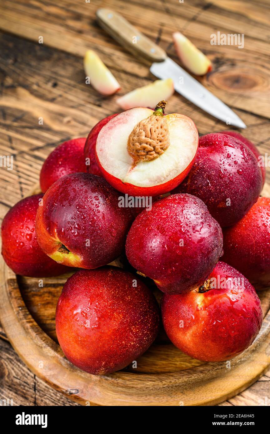 Red nectarines on a wooden tray and half a nectarine. Wooden background ...