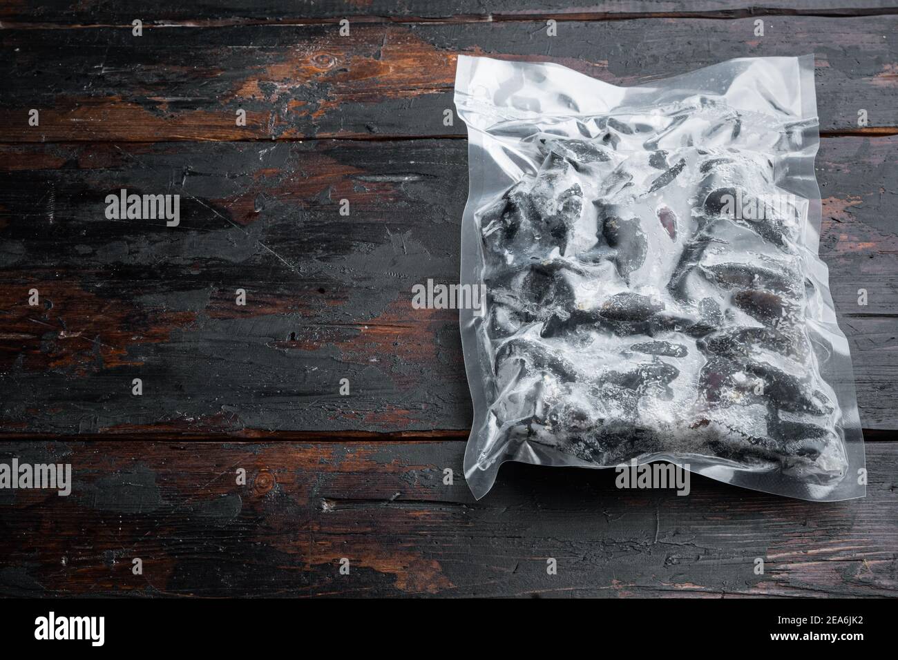 Vacuum packed whole shell mussels frozen, on dark wooden background ...