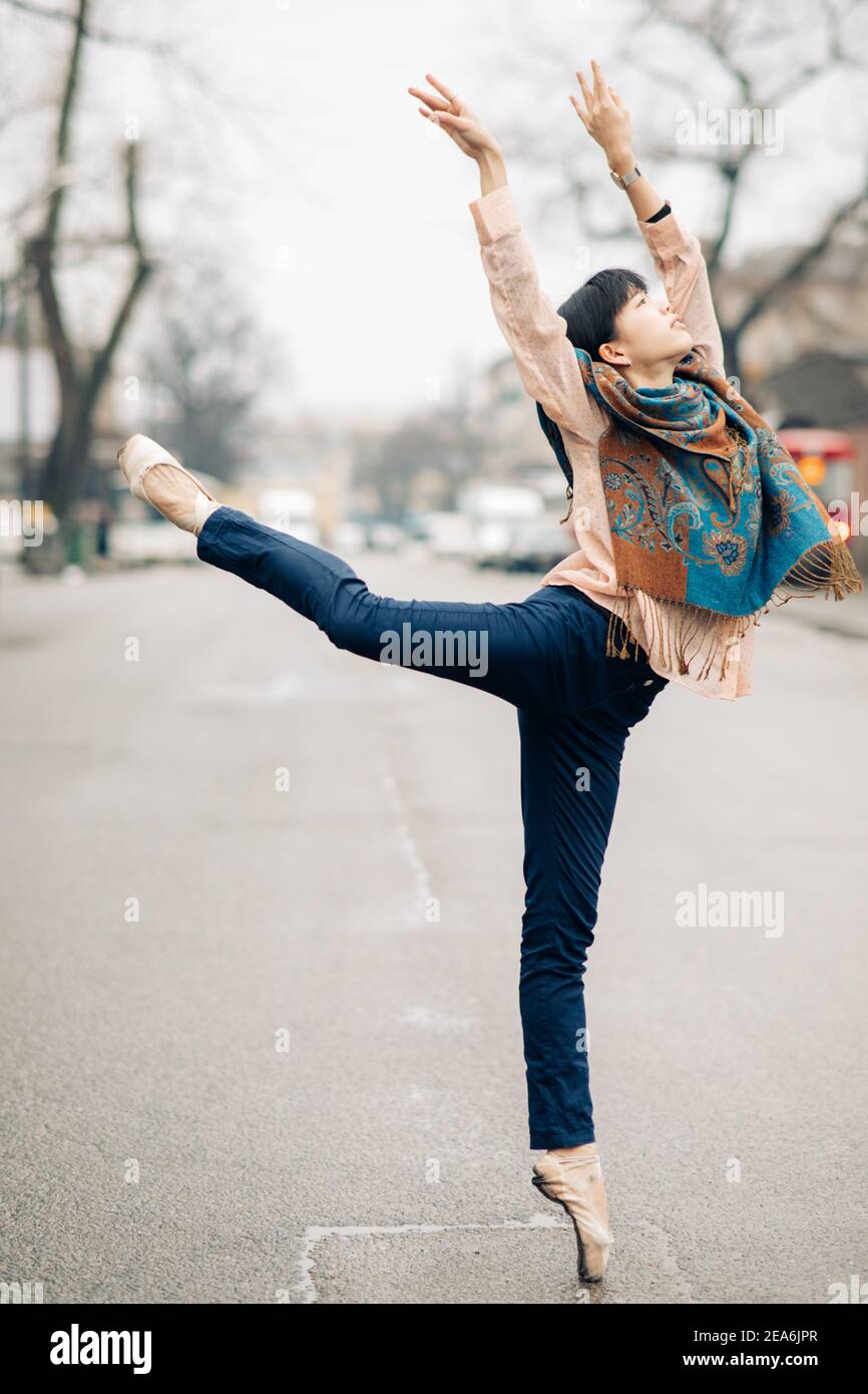 Japanese ballerina performs ballet arabesque pose among the city street ...