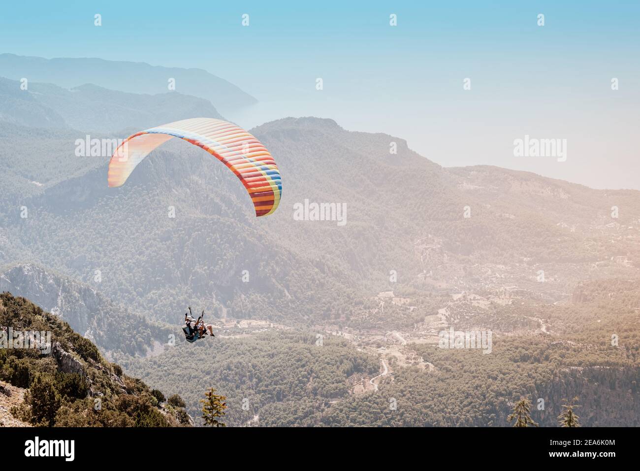A paraglider with an instructor and a student soars against the ...