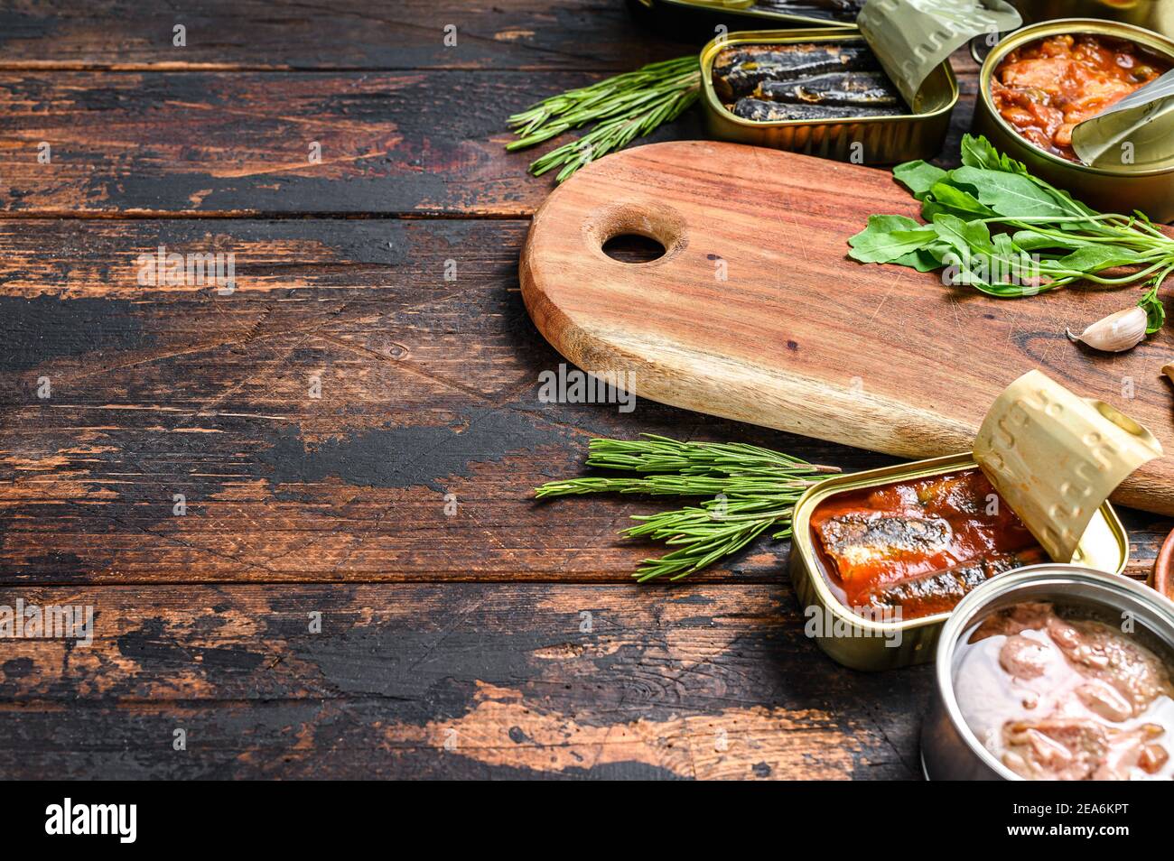 Various canned fish and seafood in a metal cans. Dark Wooden background ...