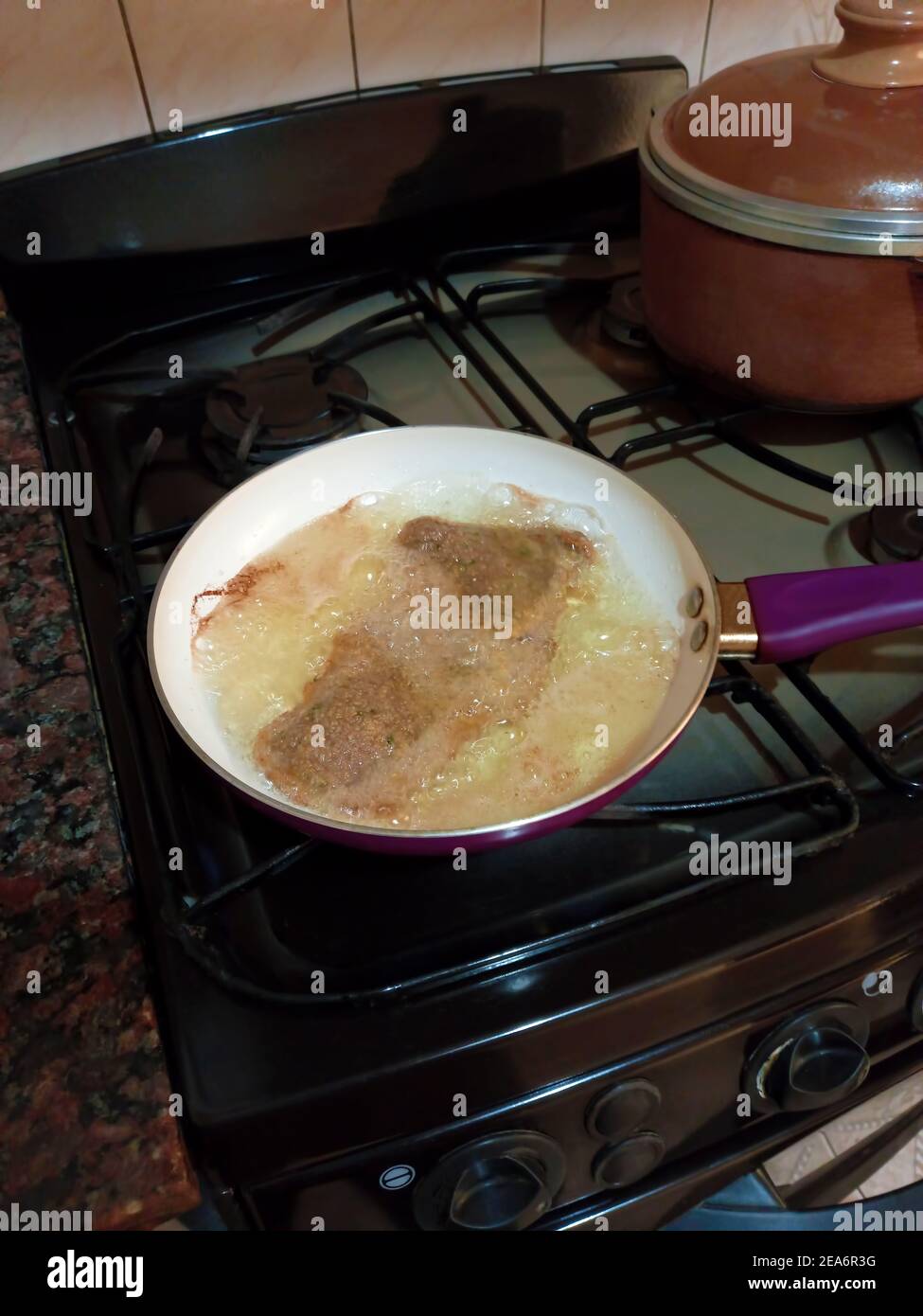 Frying a traditional tender homemade breaded veal meat cutlet Milanese ...