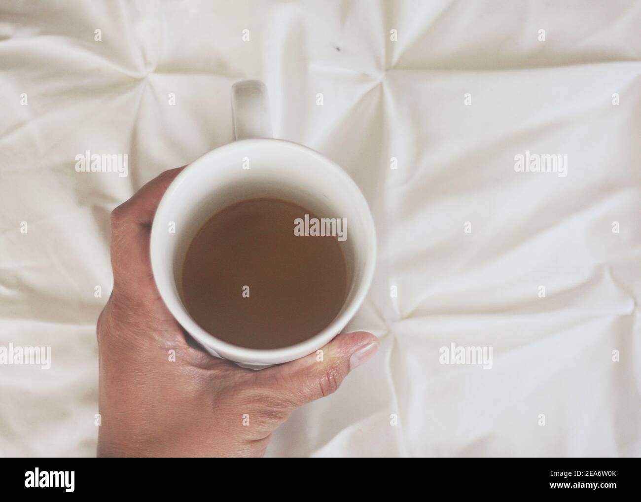 Overhead view of a hand holding a cup of tea Stock Photo - Alamy