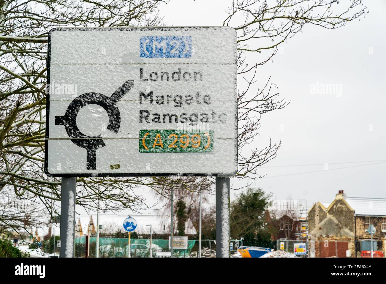 Partly covered in snow, British road sign showing a roundabout ahead ...