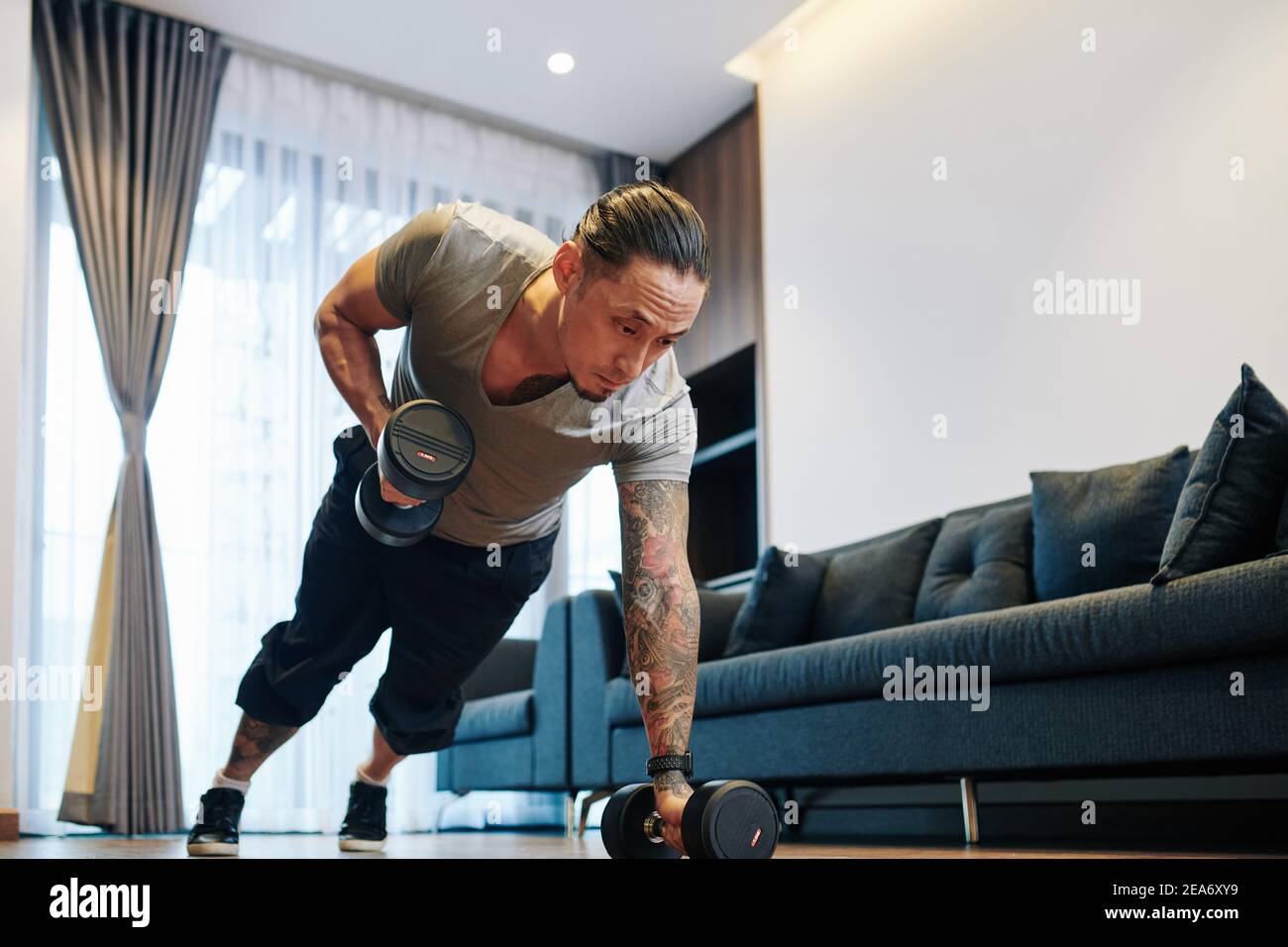 Man doing dumbbells plank row exercise Stock Photo - Alamy