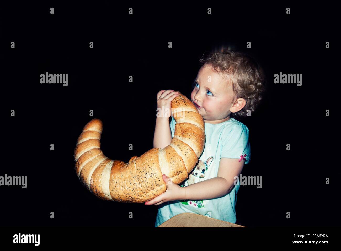 Close-up of a girl eating a giant croissant Stock Photo - Alamy