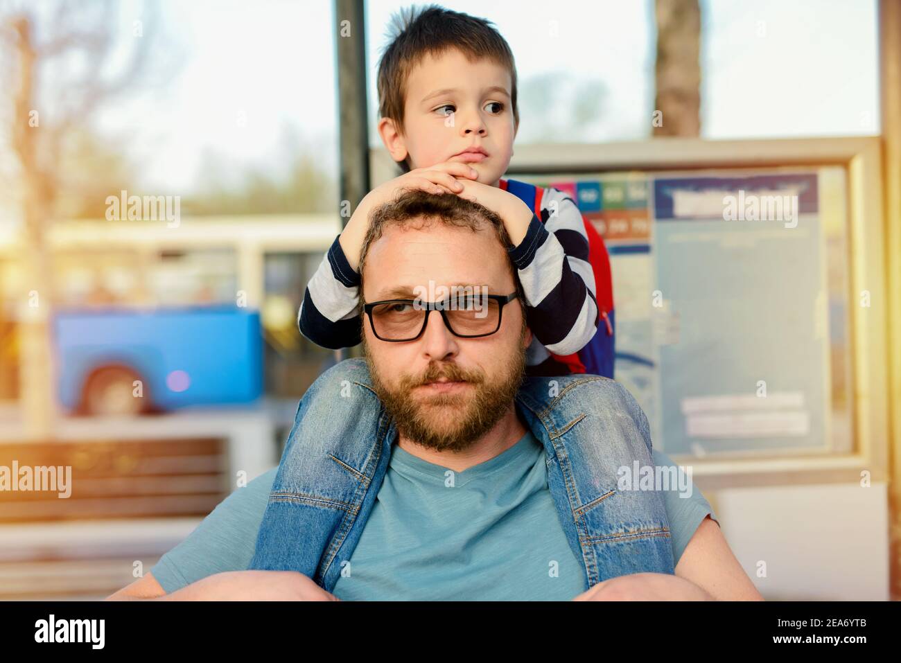 Tired father holding his son on his back while they are waiting for the ...