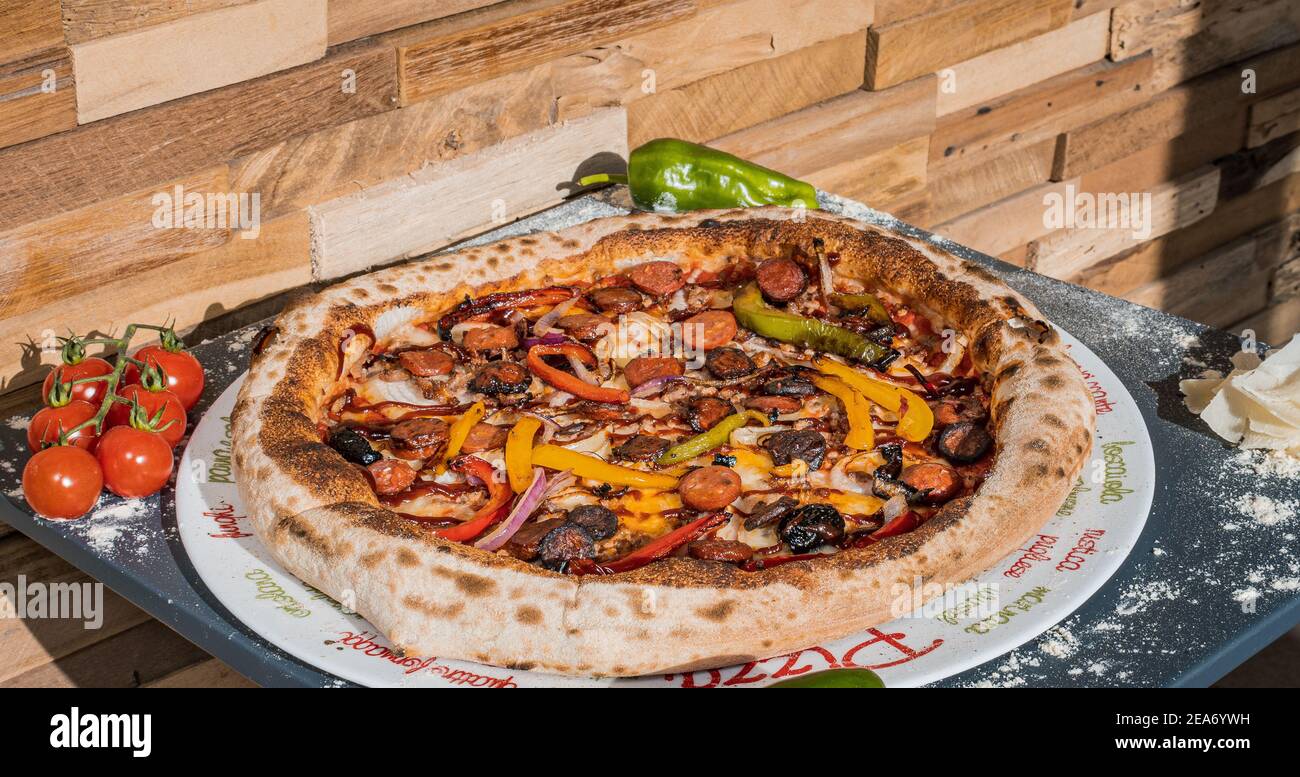 Closeup shot of an artisanal pizza crust on wood with ham and onion ...