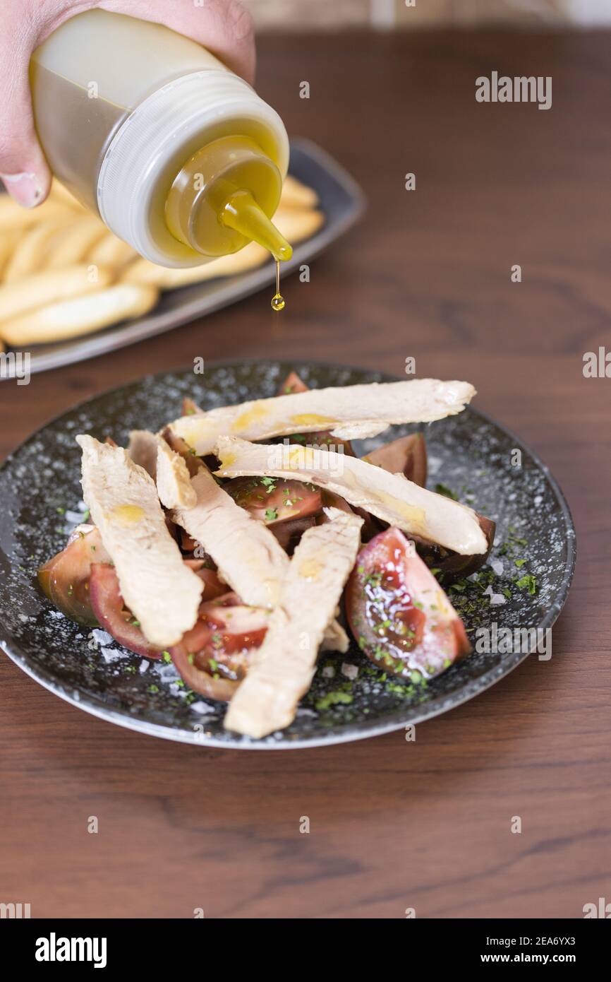 Vertical shot of pouring oil on the salad with fish belly slices and ...