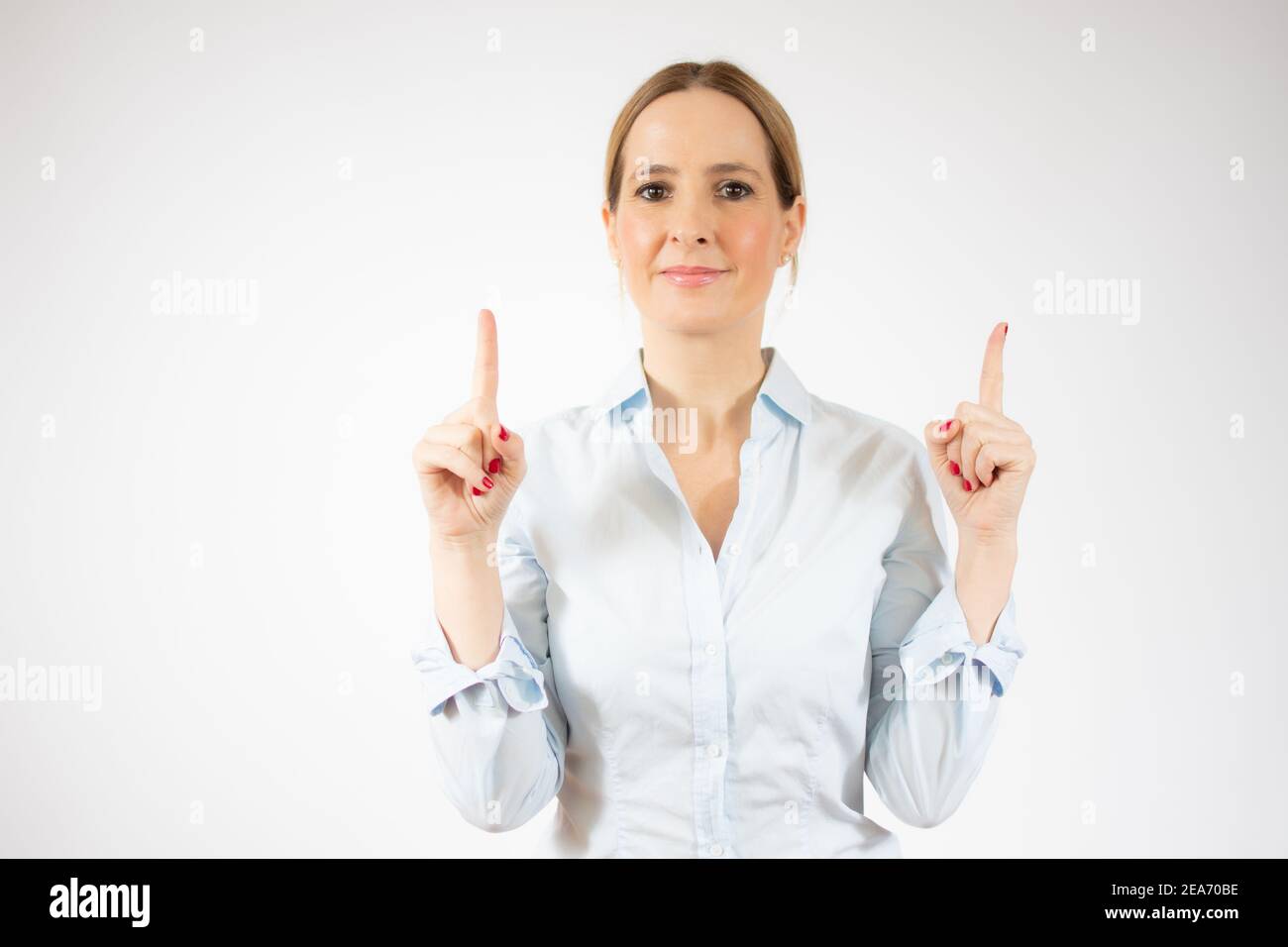 Portrait of young business woman pointing up over white background ...