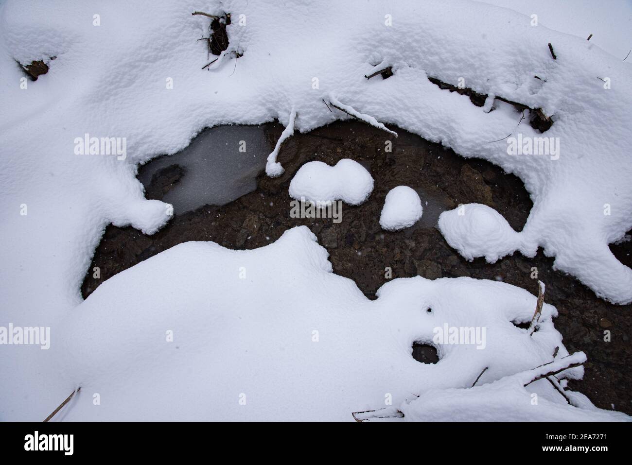 water emerges from beneath the snow, cold and clear Stock Photo - Alamy