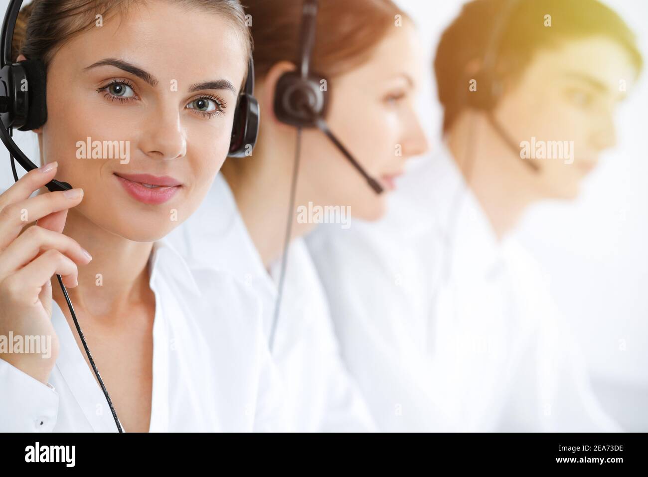 Call center. Beautiful young woman using headset and computer to help ...