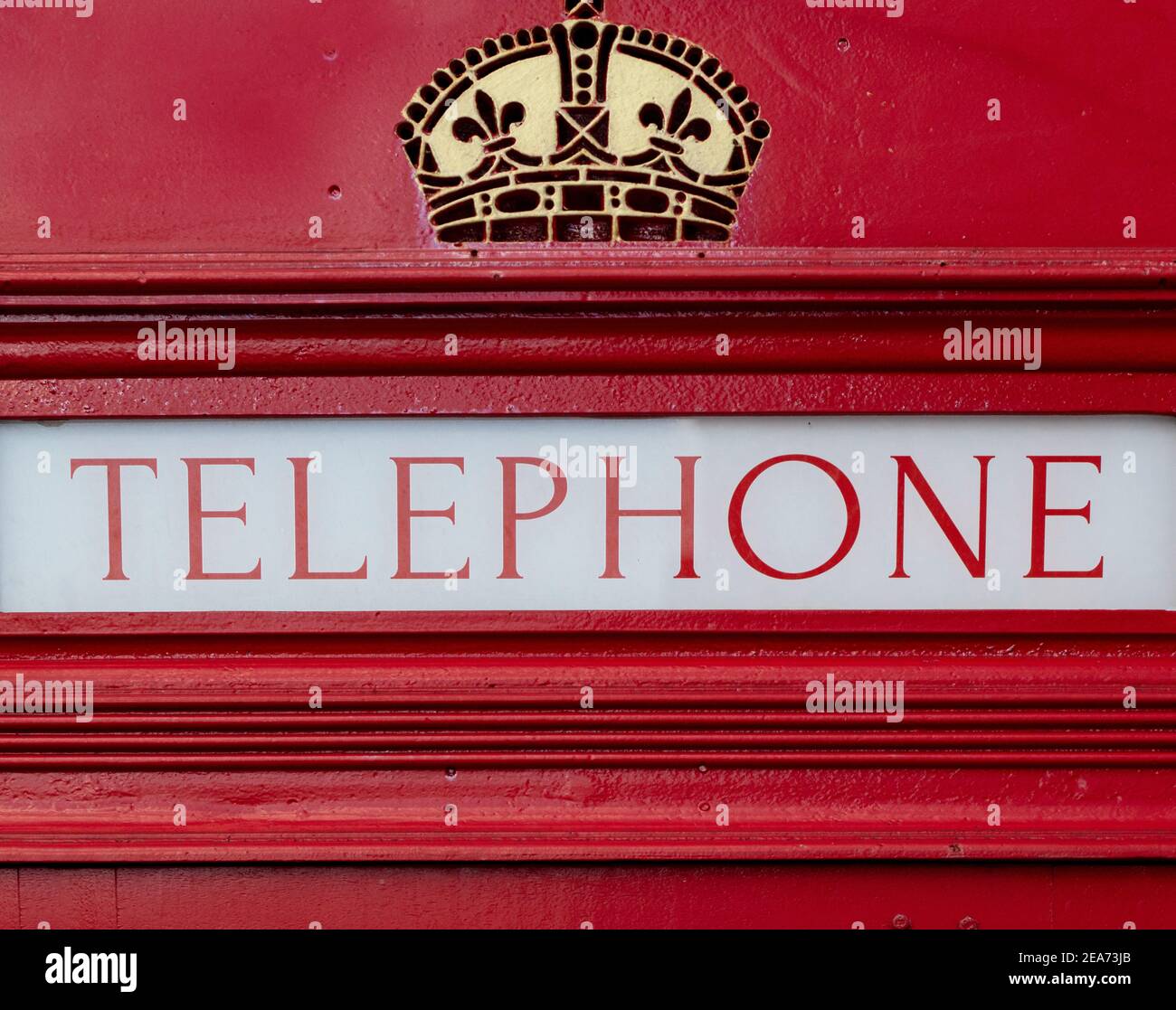 The word 'Telephone' and crown insignia on top of red telephone box ...