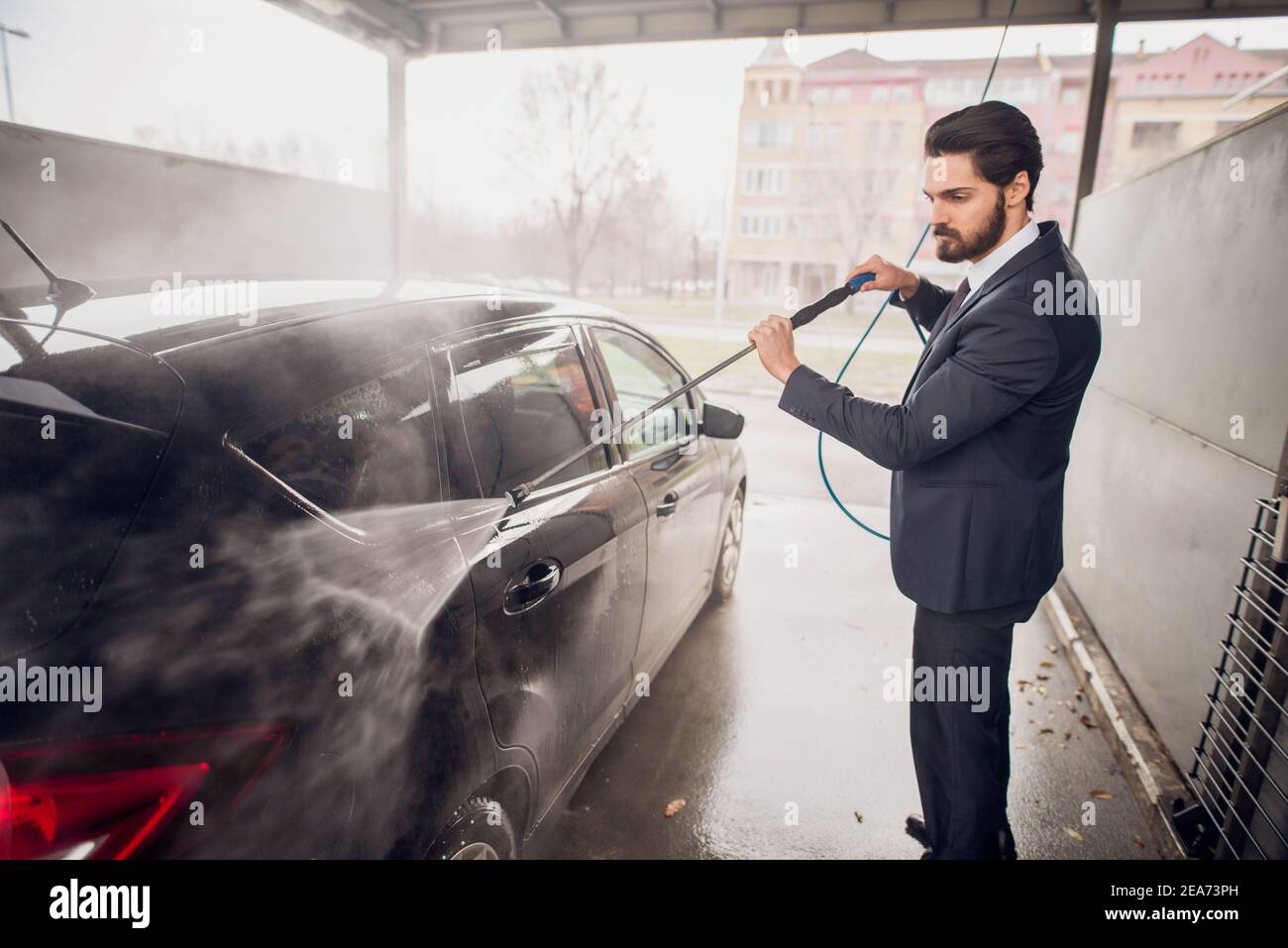 Caucasian man washing his car in car wash Stock Photo - Alamy