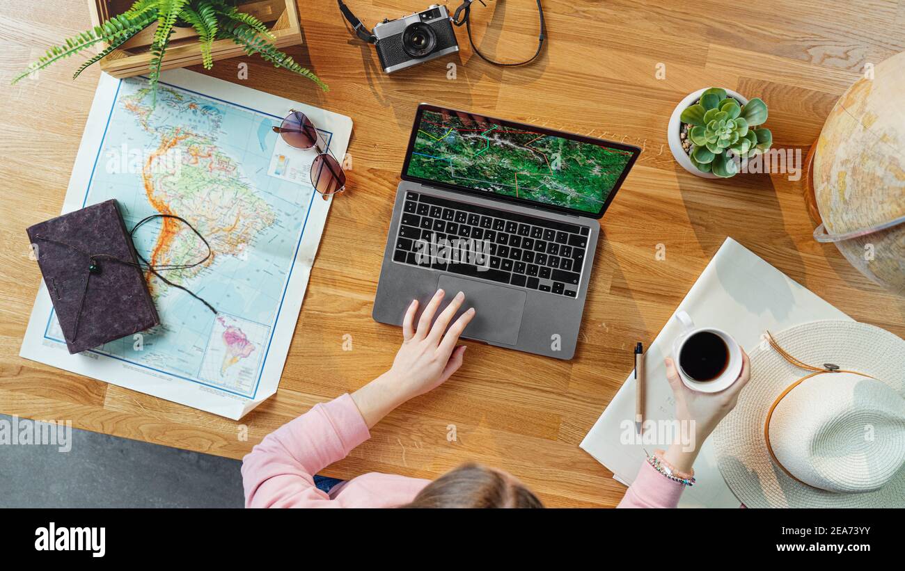 Top view of young woman with laptop and maps planning vacation trip ...