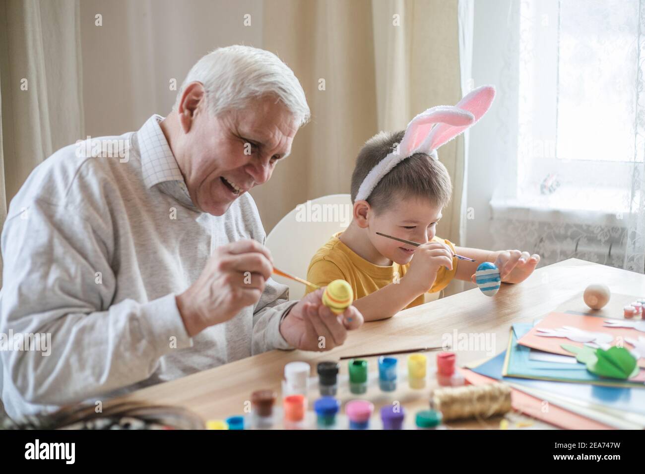 Happy elderly man granfather preparing for Easter with grandson ...