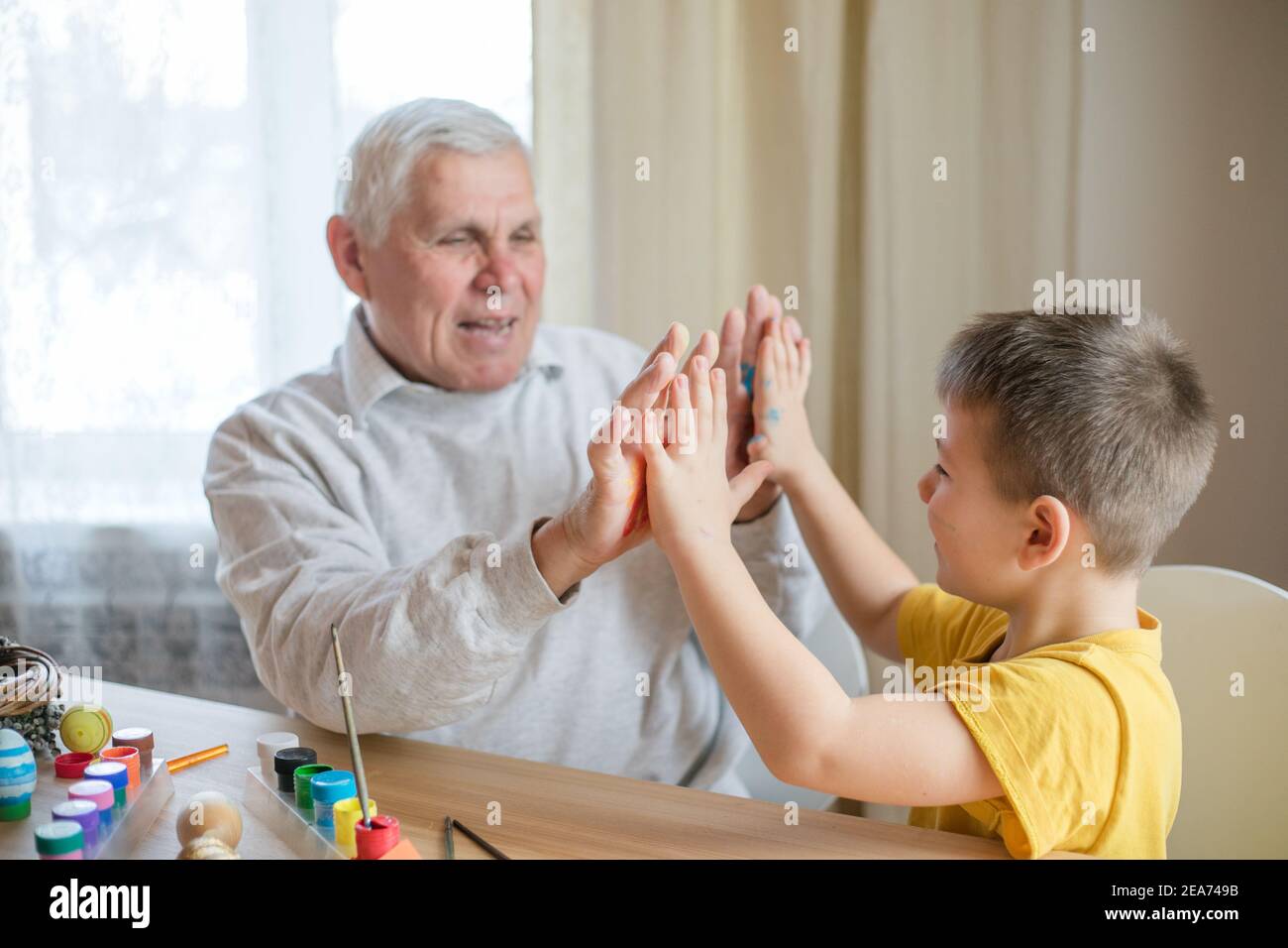 Happy elderly man granfather preparing for Easter with grandson ...