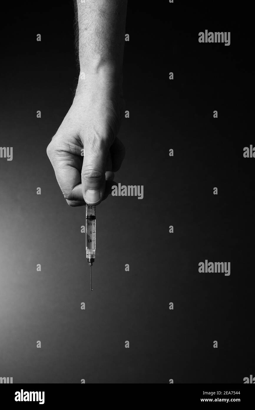 Black and white image of man's hand holding syringe vertically ...