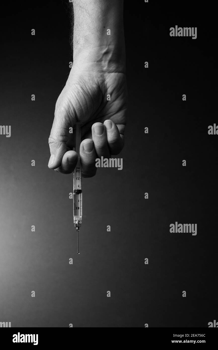 Black and white image of man's hand holding syringe vertically ...