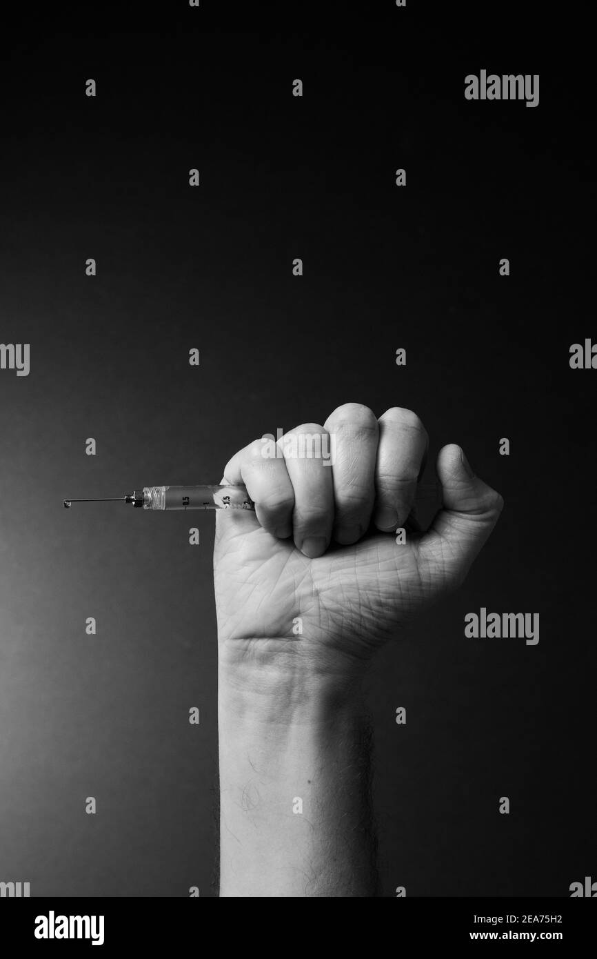 Black and white image of man's clenched hand holding syringe ...