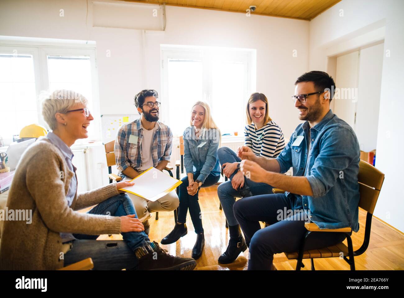 Group of people sitting in a circle on group therapy. One man is ...