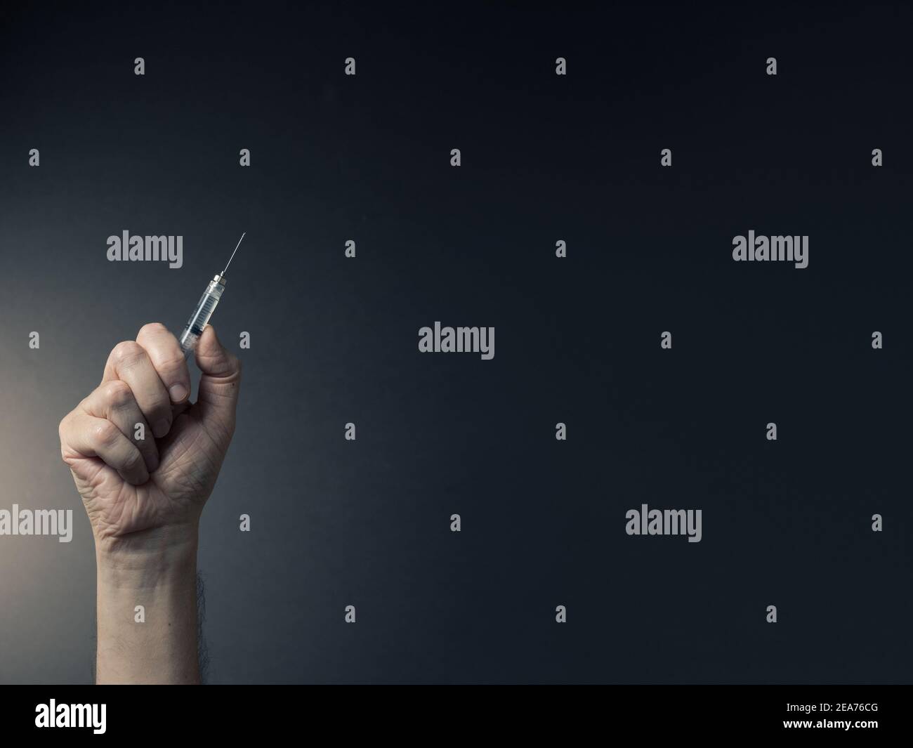 Colour image of man's clenched hand holding syringe upwards with ...
