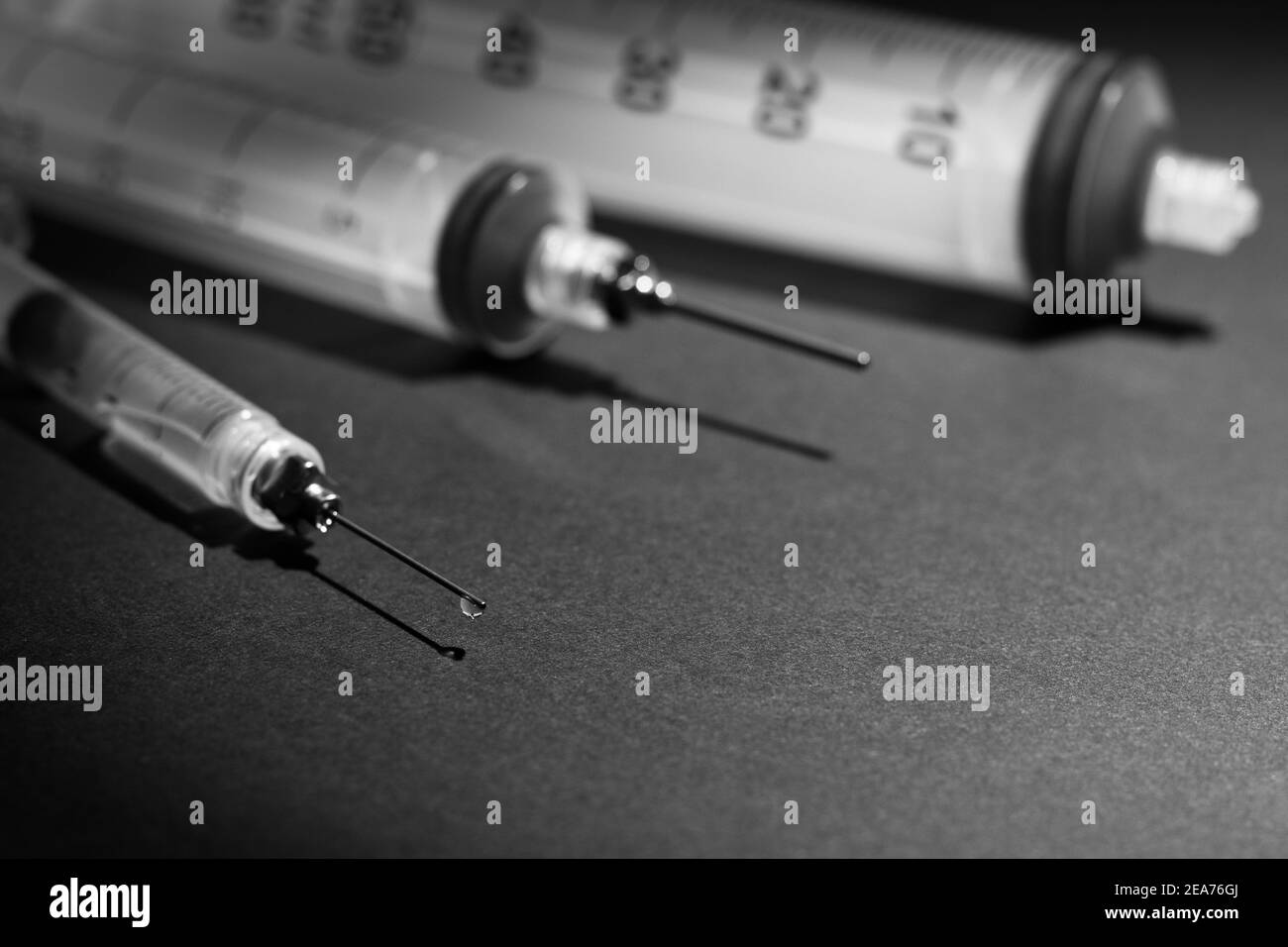 Black & white close-up image of three syringes with needles, one with ...