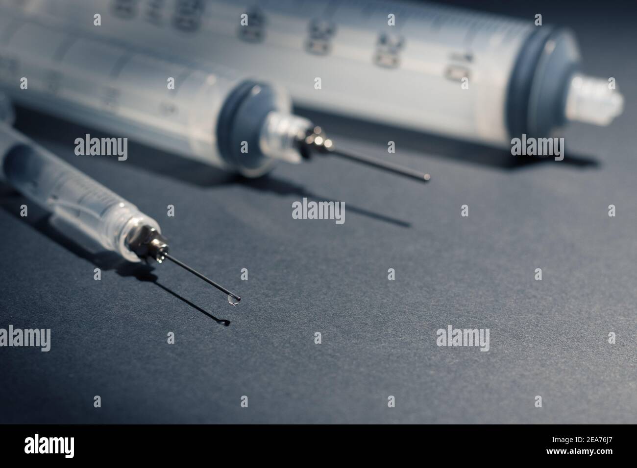 Colour close-up image of three surgical syringes with needles, one with ...