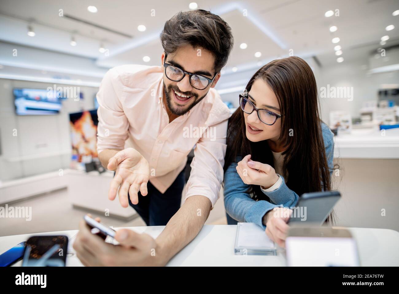 Couple comparing which smart phone is better. Man points to smart phone ...