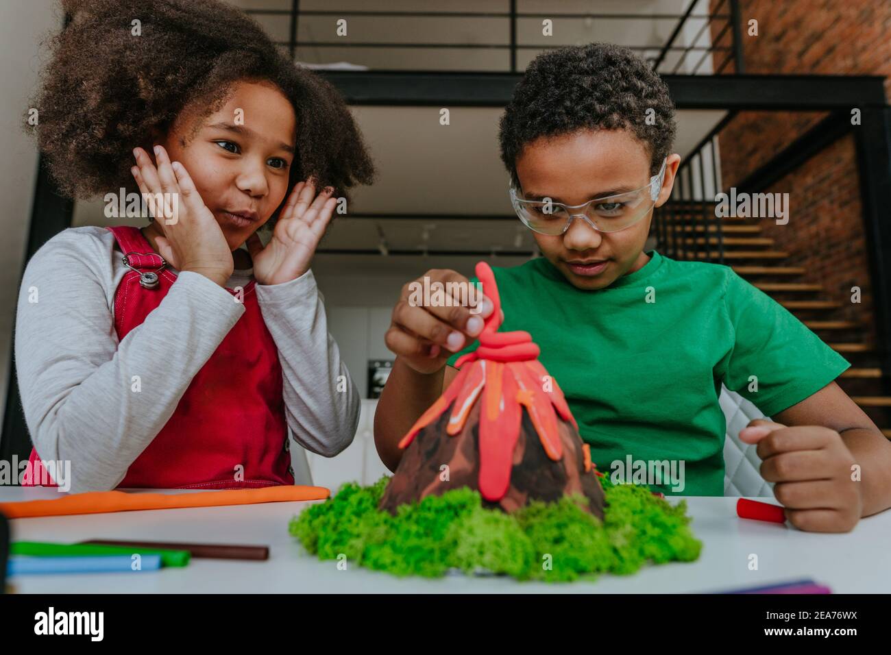 Sister and brother having fun making DIY volcano model from kids play ...