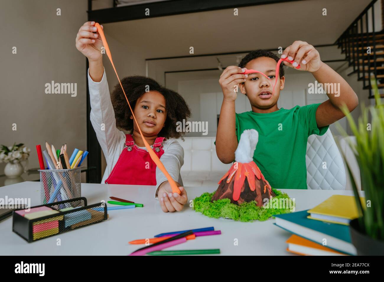 Sister and brother having fun making DIY volcano model from kids play ...