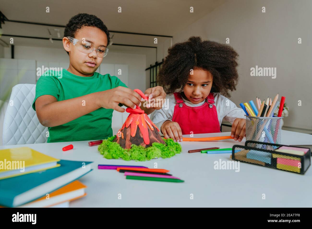 Sister and brother having fun making DIY volcano model from kids play ...