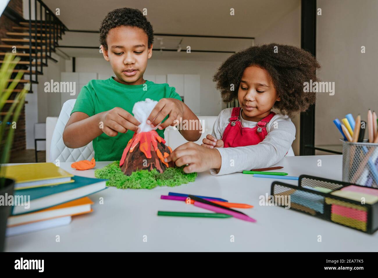 Sister and brother having fun making DIY volcano model from kids play ...