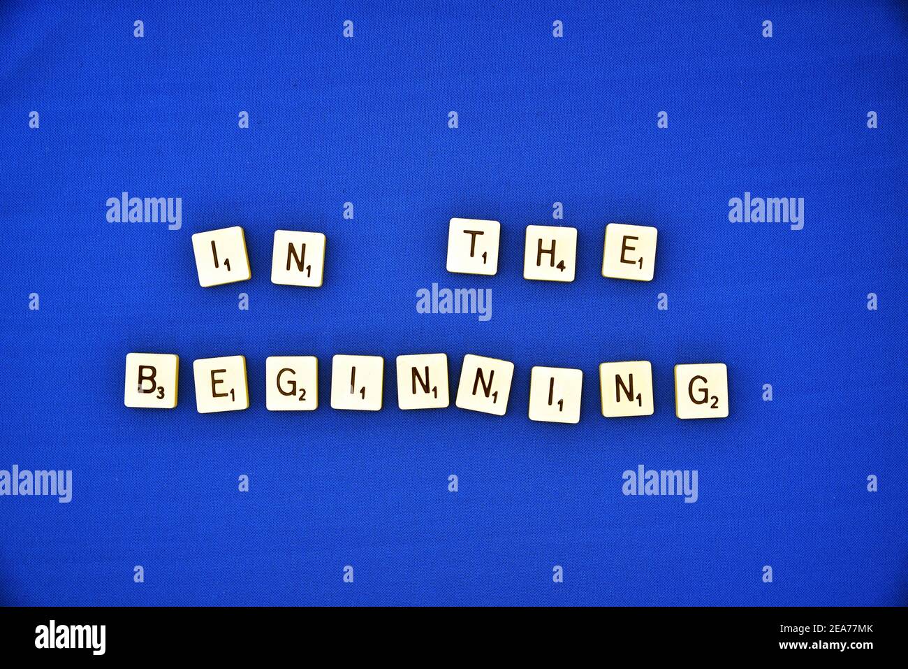Scrabble tiles on blue background spelling In The Beginning Stock Photo ...