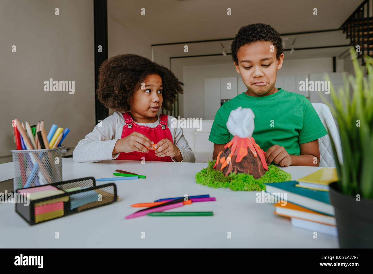 Sister and brother having fun making DIY volcano model from kids play ...