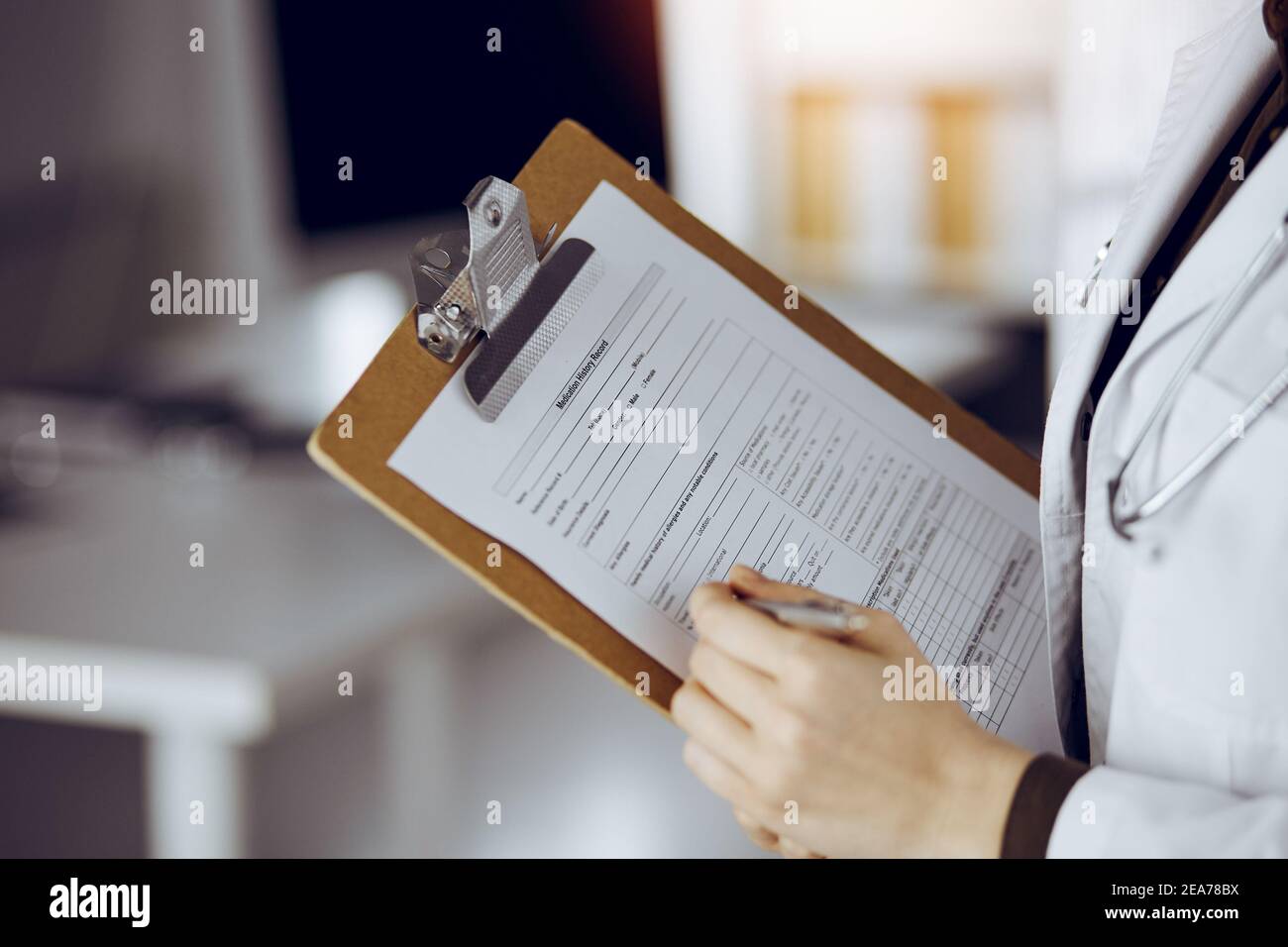 Unknown female doctor using clipboard in sunny clinic. Medicine concept Stock Photo - Alamy