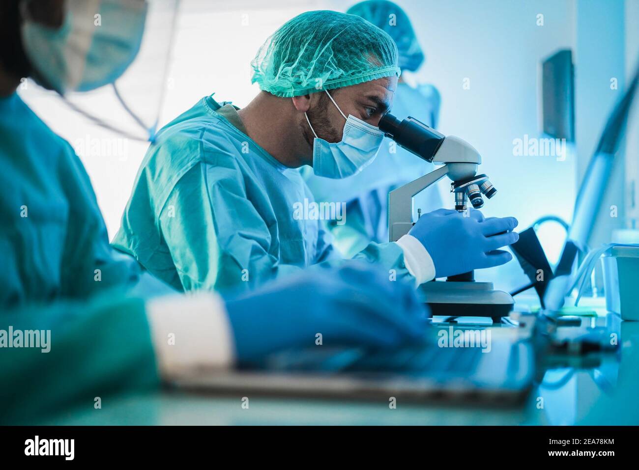 Medical workers in hazmat suit working with microscope and laptop ...