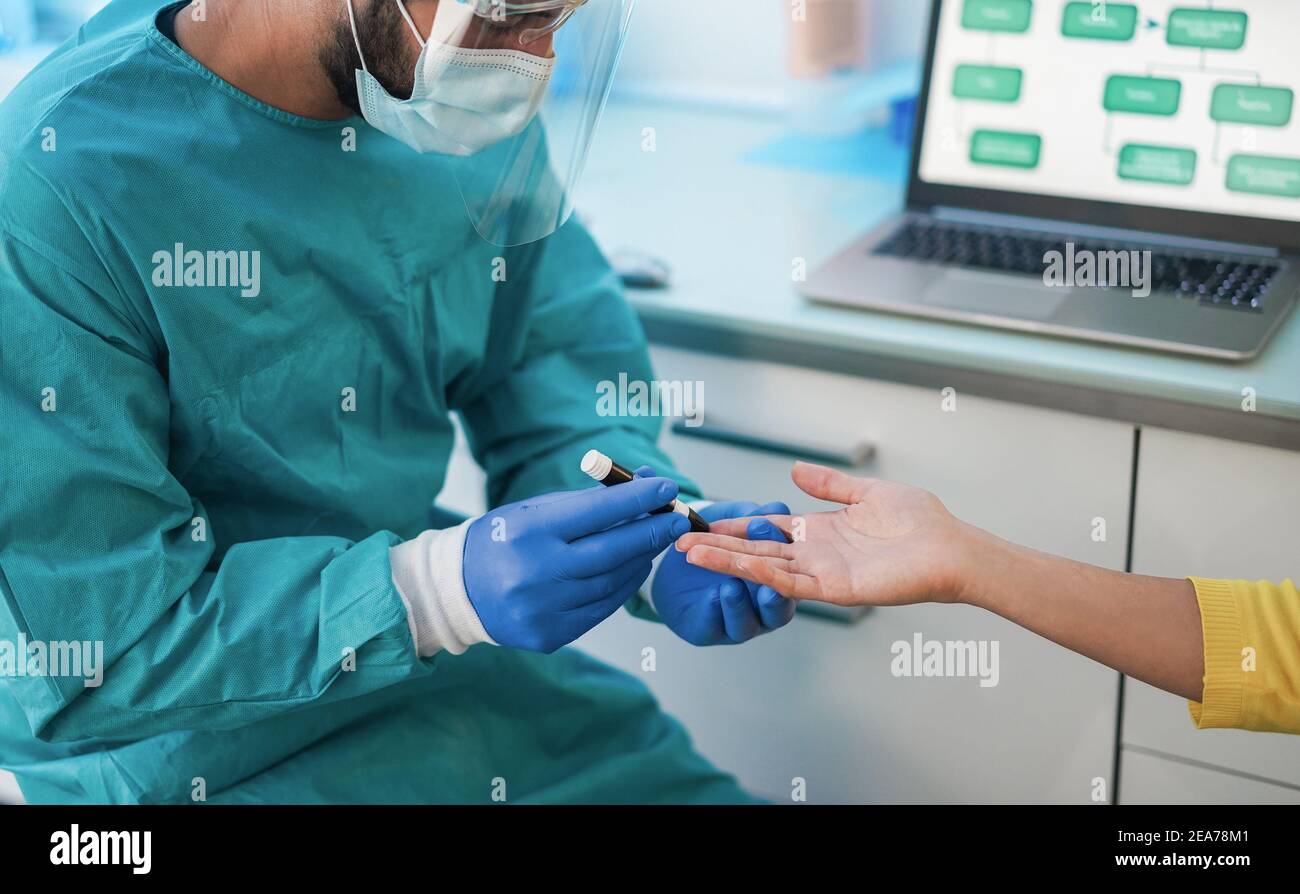 Doctor with hazmat suit and protective gloves checking blood sugar ...