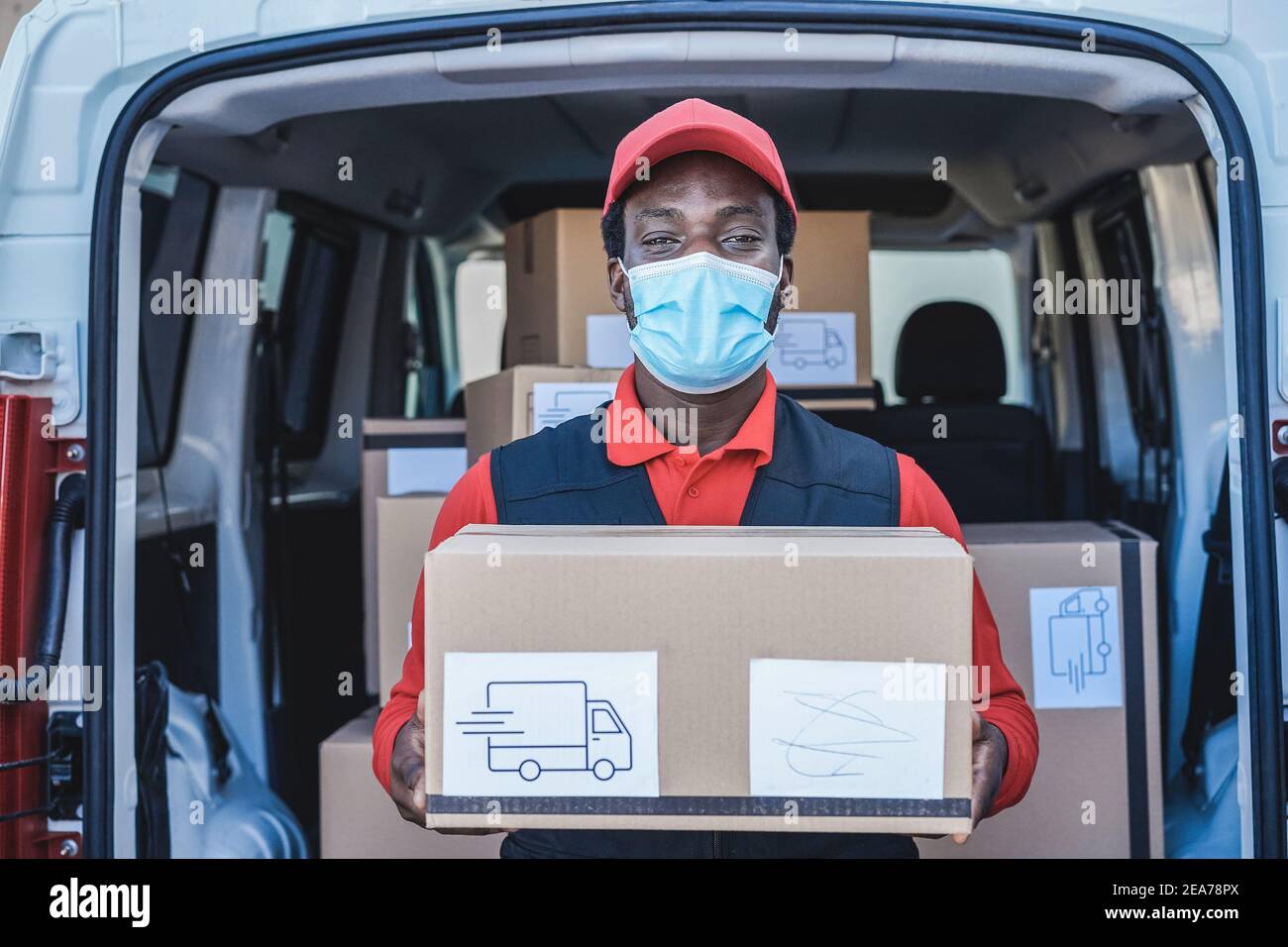 Black courier man delivering package in front of cargo truck wearing ...