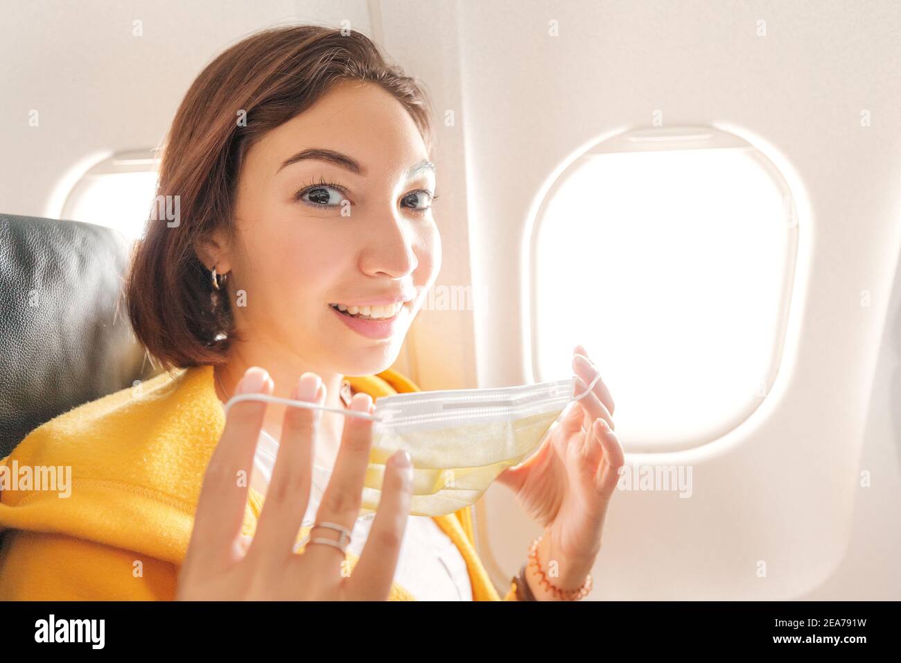 An Asian girl wears a medical face mask during an airplane flight ...