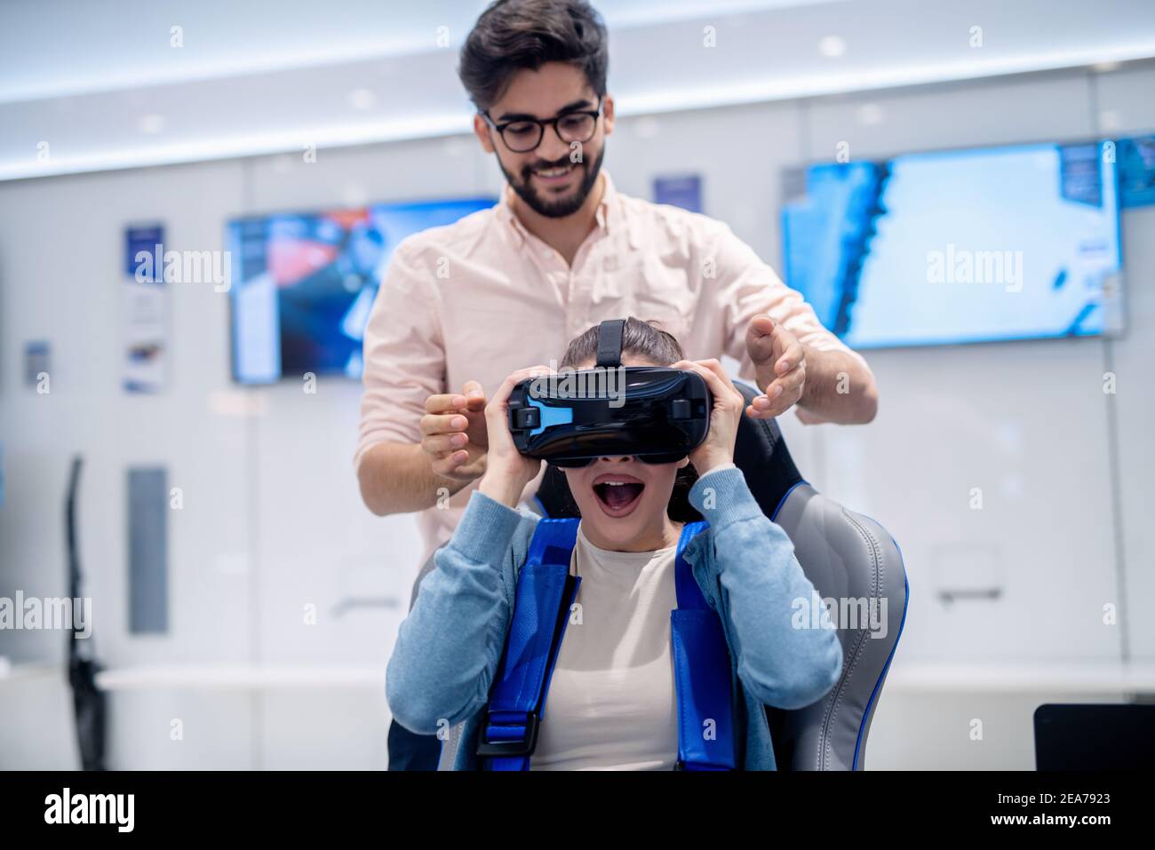Amazed woman looking through VR glasses while sitting on interactive VR ...